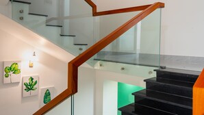 Uma escadaria moderna com guarda-corpos de vidro e degraus de madeira.
