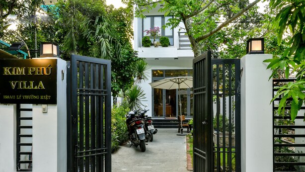 Uma entrada com portão para a Kim Phu Villa, com um caminho bem definido que leva ao edifício principal.