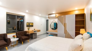 Quarto de hotel moderno com uma cama grande, uma escrivaninha, uma cadeira e um sofá.