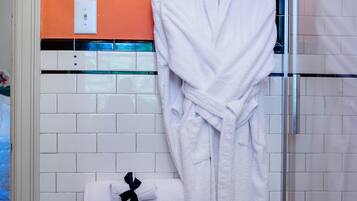 Um banheiro com uma banheira branca, um porta-toalhas branco e um roupão branco pendurado na parede.