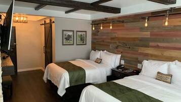 Quarto de hotel com duas camas, cabeceira de madeira e escada com televisão.