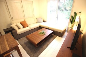 Sala de estar com sofá, mesa de centro, televisão e planta.