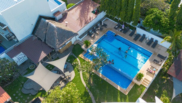 Vista aérea de uma propriedade com piscina, espreguiçadeiras e área de jardim.