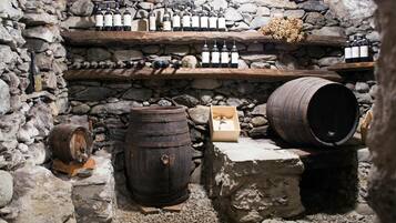 Uma parede de pedra com garrafas de vinho e barris de madeira.