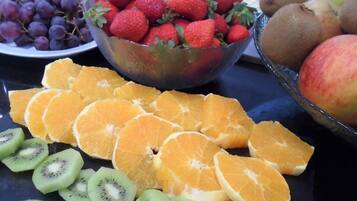Uma mesa com uma variedade de frutas, incluindo uvas, morangos, kiwis, laranjas e maçãs.