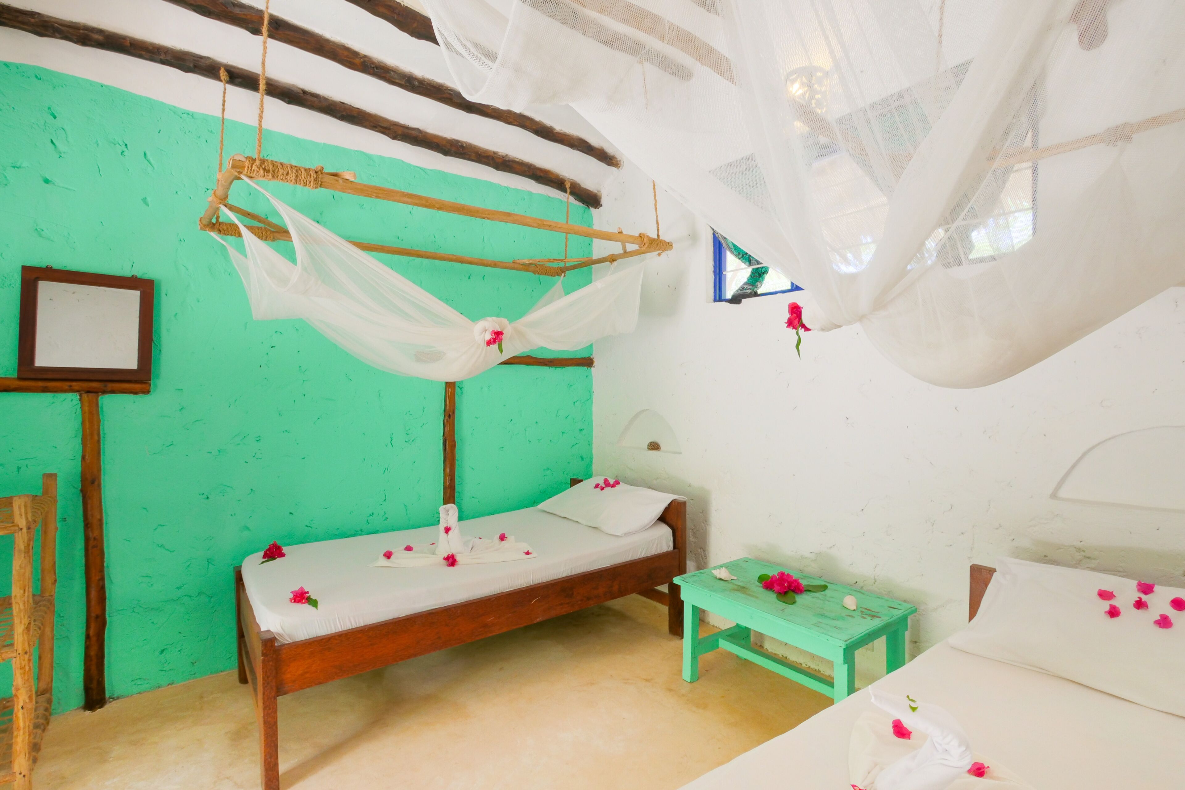 Um quarto com cama, uma mesinha e uma cadeira suspensa.