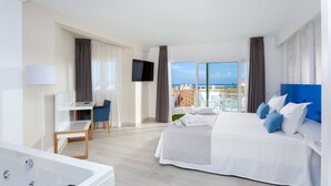 Quarto de hotel moderno com uma cama grande, uma escrivaninha e uma televisão.