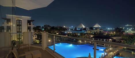 Piscina no terraço com vista para as pirâmides à noite.