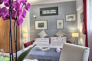 Quarto com cama, duas almofadas, mesa de cabeceira, abajur e janela.