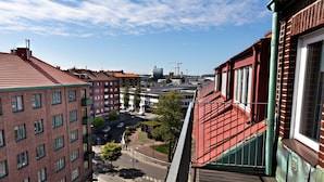 Um edifício alto com várias janelas e varandas, uma rua abaixo e um canteiro de obras ao longe.