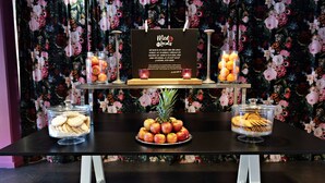 Uma mesa com frutas, biscoitos e velas, com um letreiro que diz 'Conheça os moradores locais'.