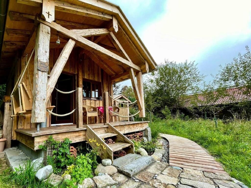 Uma cabana de madeira com varanda, degraus de pedra e um caminho de madeira que a leva até ela.