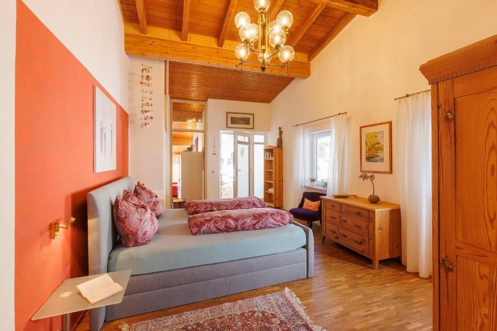 Quarto com cama, escrivaninha, guarda-roupa e lustre.