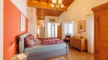 Quarto com cama, escrivaninha, guarda-roupa e lustre.