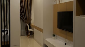 Uma sala de estar moderna com uma televisão de tela plana fixada em um painel de madeira, um sofá branco e uma pequena mesa com uma planta.