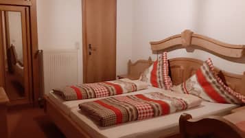 Quarto com duas camas, cabeceiras de madeira e roupa de cama xadrez.