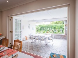 Um espaço de estar integrado com área de jantar, cozinha e um pátio com vista para um jardim exuberante.