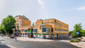 Um edifício com placa indicando 'Mehilainen' e 'Balanssi' no andar térreo, apresentando um estilo arquitetônico moderno, com janelas amplas e telhado plano.