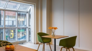 Um interior moderno com uma janela grande, uma mesa com cadeiras e uma cesta de frutas.