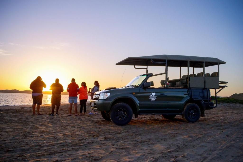 Um veículo estacionado na praia com o pôr do sol ao fundo.