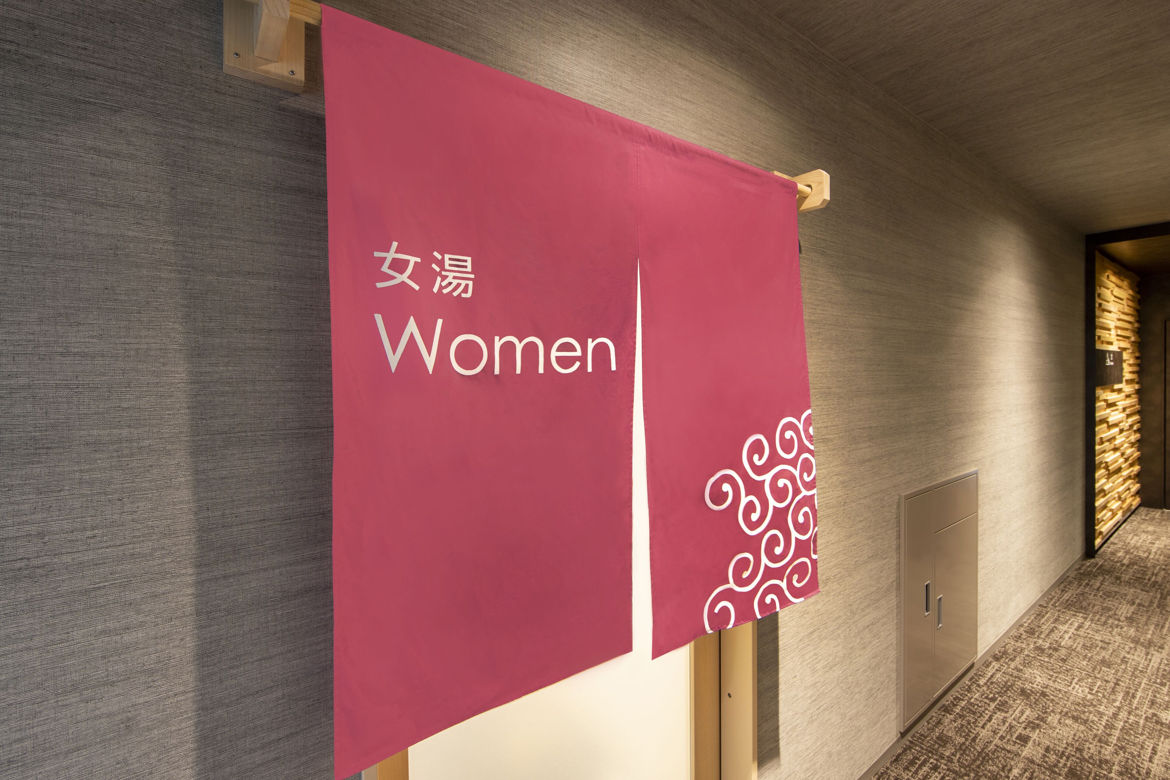 Um corredor com um banner vermelho com a palavra 'Women' e um padrão decorativo.