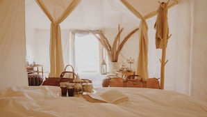 Um quarto com cama de dossel, mesa de cabeceira com abajur e janela com luz natural.