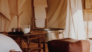 Um quarto acolhedor com uma mesa de madeira, um banquinho de couro e uma cama.