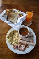 Prato de café da manhã com torradas, sopa e bacon sobre uma mesa de madeira.