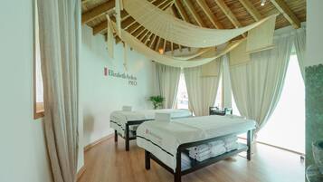 Quarto com duas camas, teto de madeira e um letreiro com a inscrição 'Elizabeth Arden PRO'.