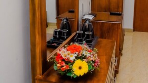 Um balcão de madeira na receção com um espelho, uma máquina de café e uma composição floral.