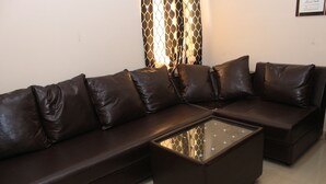Um sofá modular de couro marrom com uma mesa de centro de vidro em uma sala de estar moderna.