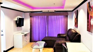 Uma sala de estar moderna com um sofá, uma TV fixada na parede e uma cortina.