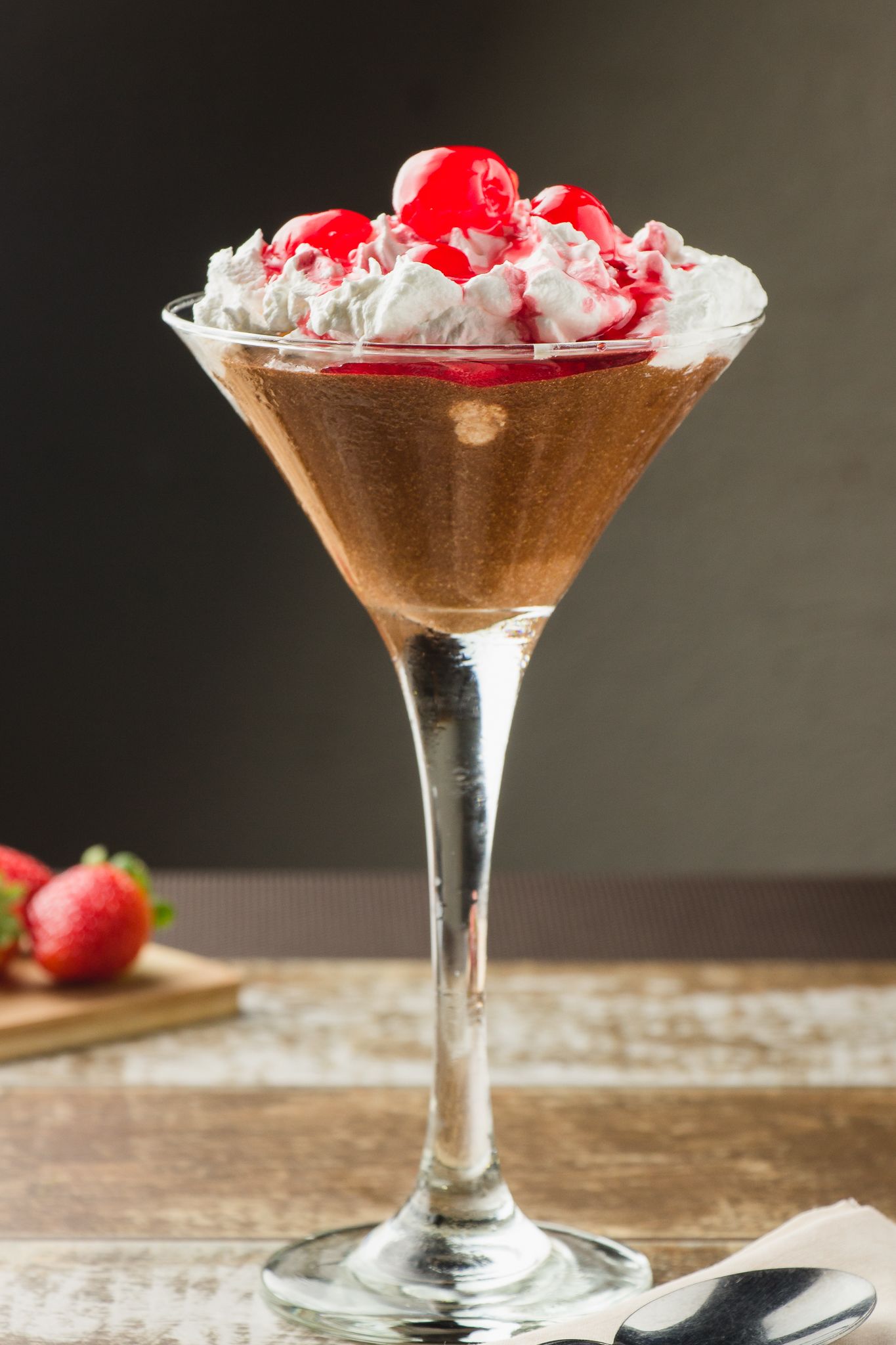 Uma sobremesa em taça martini, com chantilly e cerejas por cima.