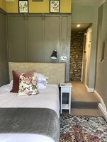 Um quarto com uma cama, mesa de cabeceira, abajur e tapete.