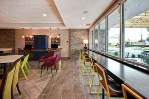 Um restaurante com um balcão extenso, várias áreas de estar e vista para o exterior.