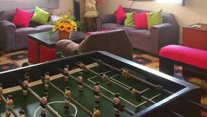 Uma sala de estar com dois sofás, uma mesa de futebol de bolso, um candelabro e uma estátua.