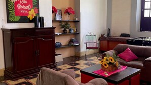 Uma sala de estar com sofá, mesa de centro, televisão, lustre e um quadro na parede.