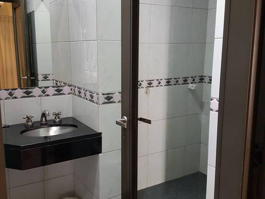 Casa de banho com lavatório preto, azulejos brancos e divisória de chuveiro em vidro.