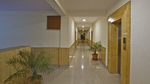 Um corredor com portas de madeira, um vaso com planta e uma placa na parede.