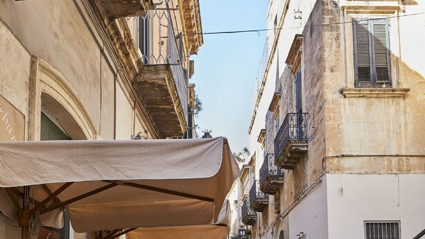 Uma rua estreita com mesas ao ar livre e um café.