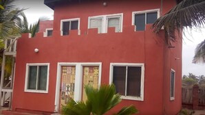 Um edifício vermelho de dois andares com várias janelas e uma porta com detalhes decorativos.