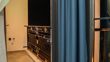 Uma porta aberta que dá para uma varanda com grade de metal e vista do céu noturno.