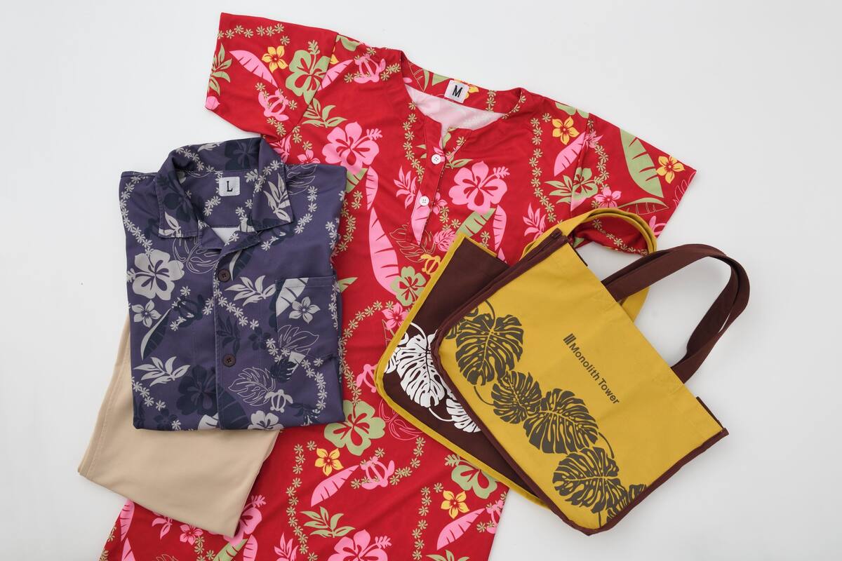 Uma camisa vermelha com estampas florais, uma camisa azul com estampas florais, uma camisa bege e uma bolsa de tecido amarela com design floral.