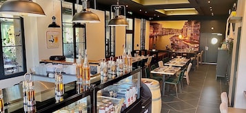 Interior de restaurante com um balcão comprido, luminárias pendentes e um mural de uma paisagem urbana.