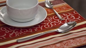 Uma tigela branca sobre um prato branco em uma toalha de mesa listrada.