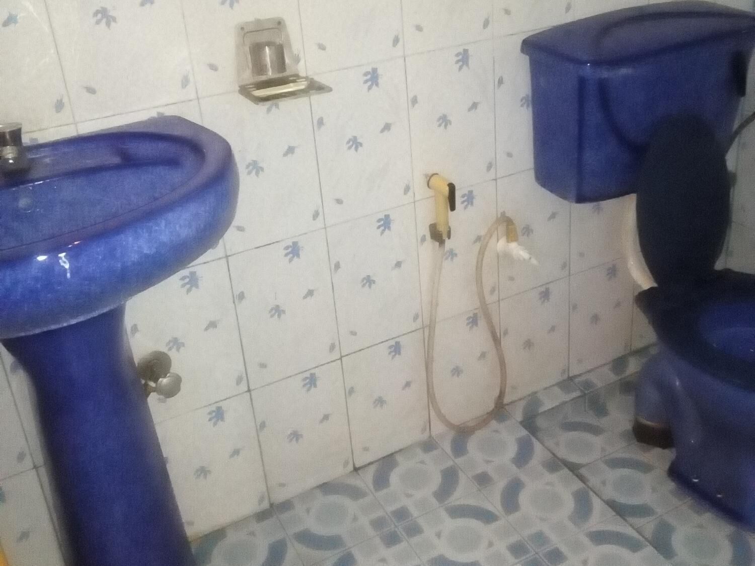 Casa de banho com lavatório azul, sanita e azulejos estampados.