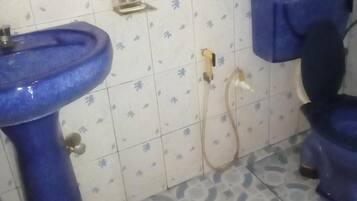 Casa de banho com lavatório azul, sanita e azulejos estampados.