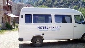 Uma carrinha branca com a inscrição 'HOTEL EXARI' e informações de contacto na lateral.