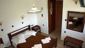Quarto com cama grande, mesas de cabeceira, um banco, espelho e luminária suspensa.