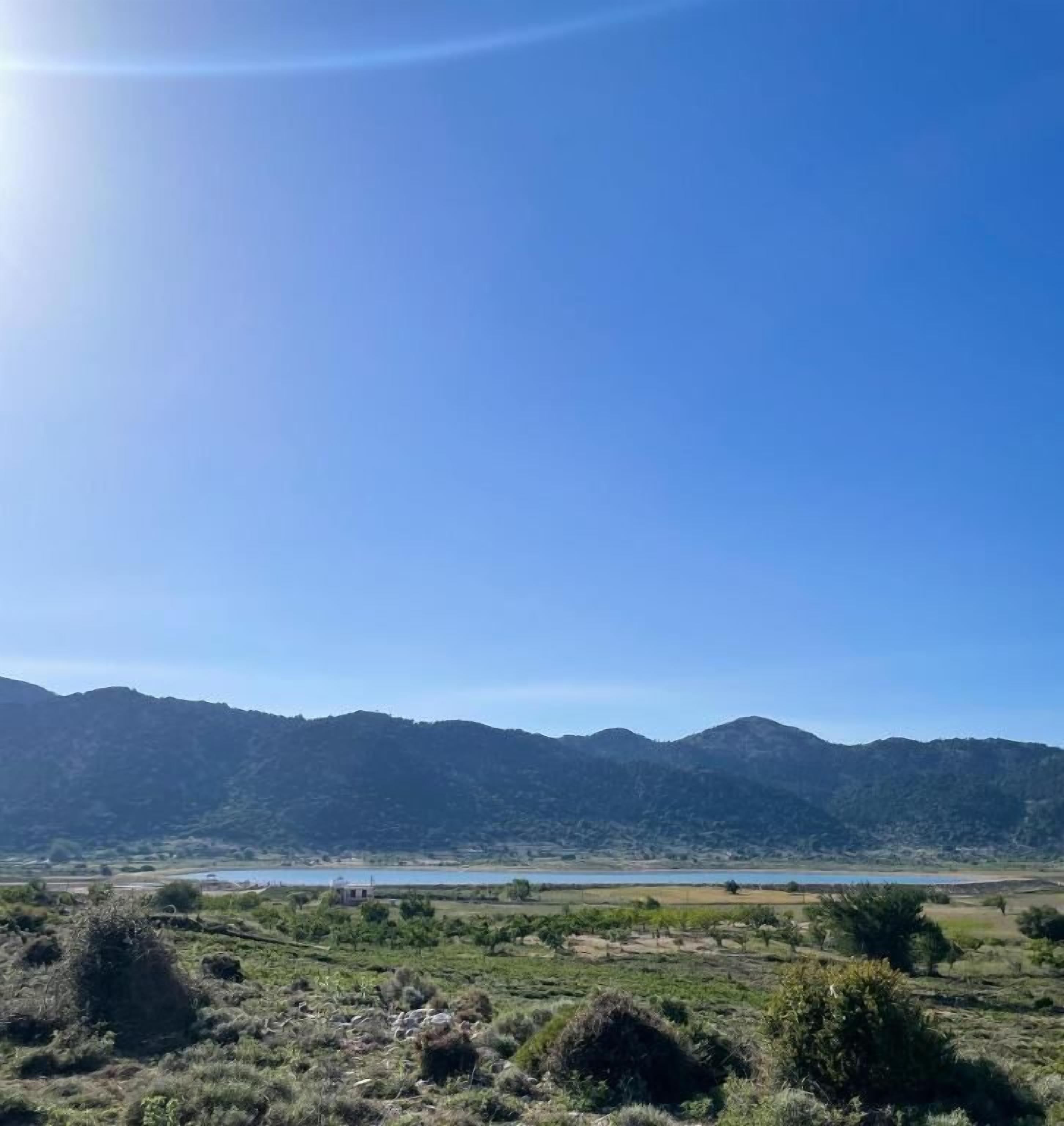 Paisagem com um corpo d'água, colinas e vegetação rala.